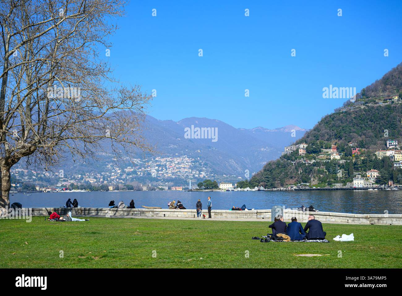 People sitting in a park in front of Lake Como – Como, Italy – 05 March ...