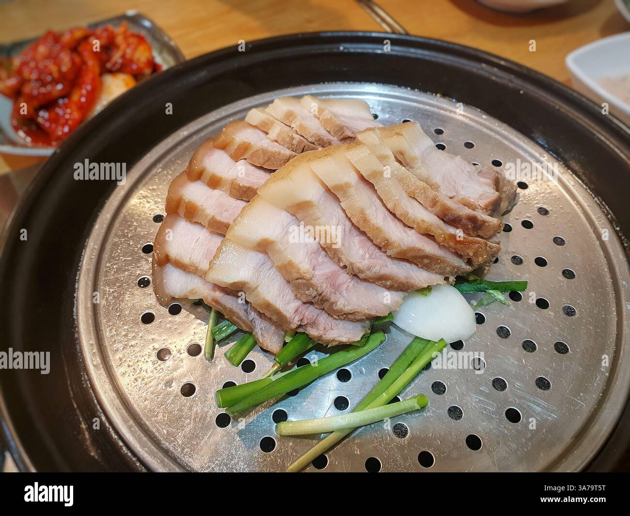 Tender, sliced Korean bossam (boiled pork belly) served on a steaming ...