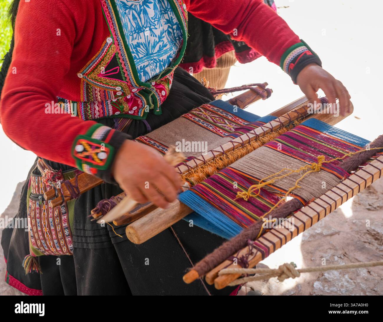 An artisan near Cusco, Peru, weaves a traditional textile using a ...
