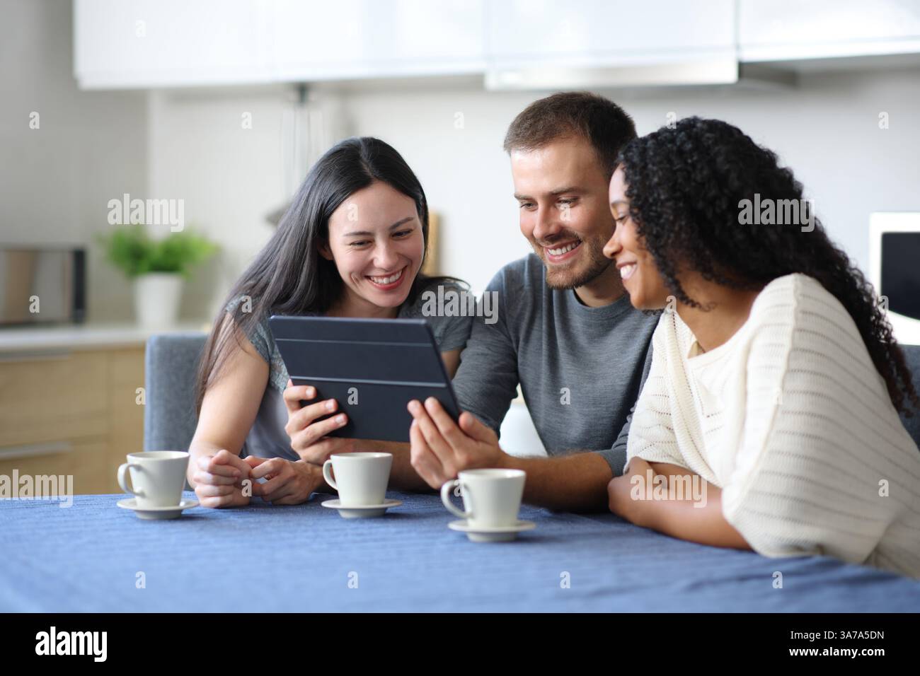 Happy Interracial Roommates Watching Media On Tablet In The Kitchen At 2581