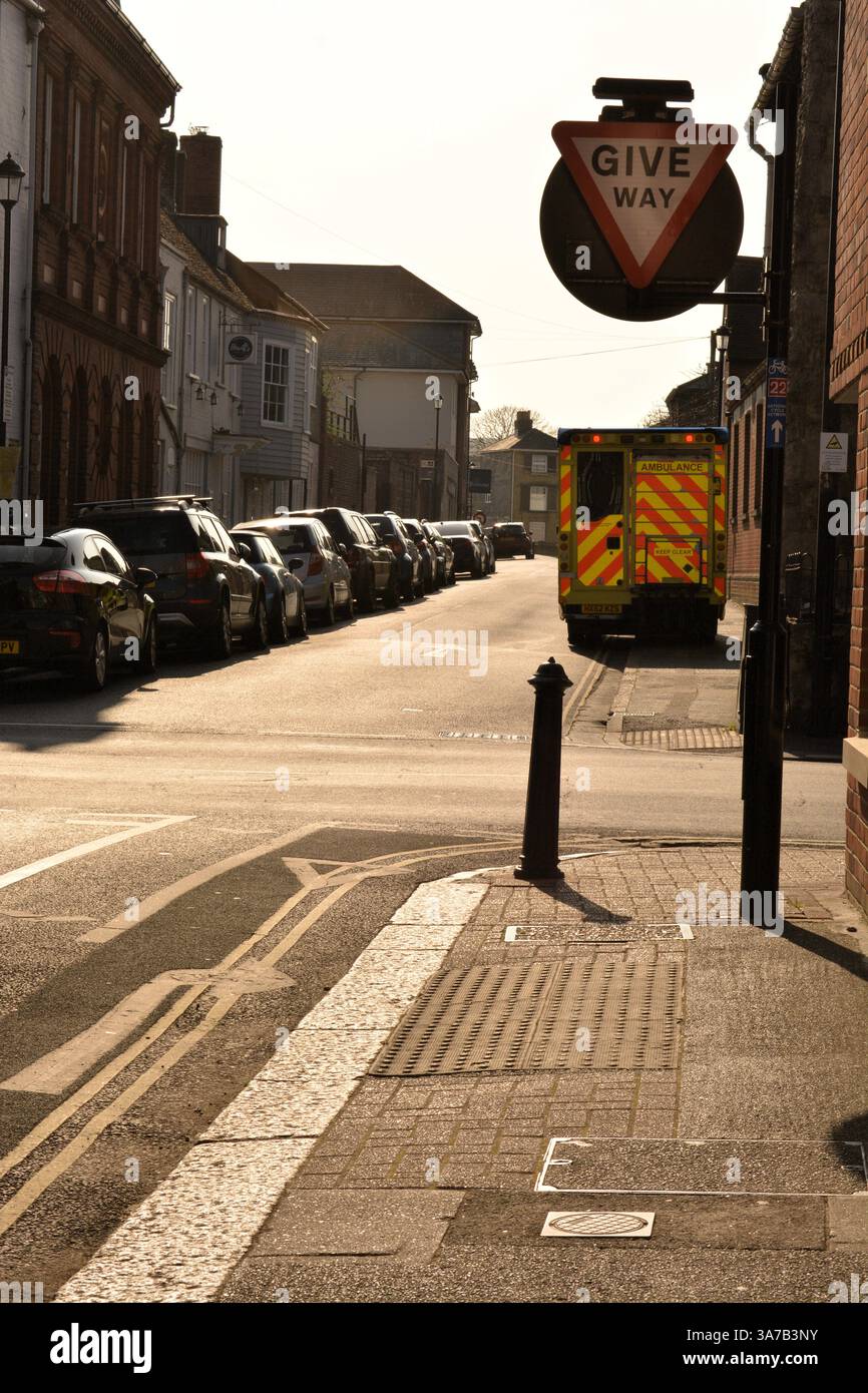 Street scene mid-afternoon, strong light and shade ambulance stationary ...