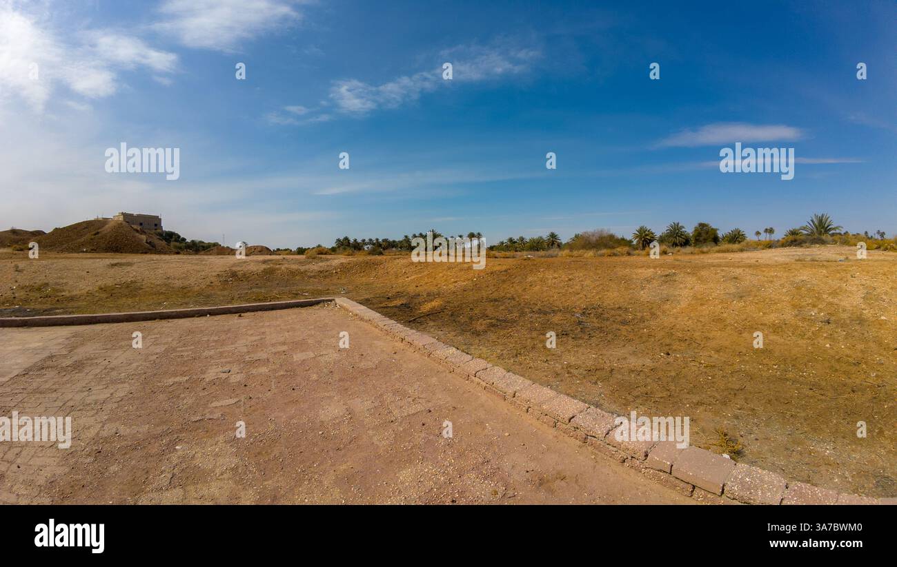 A wide landscape view of a dry, arid terrain with a clear blue sky. The ...
