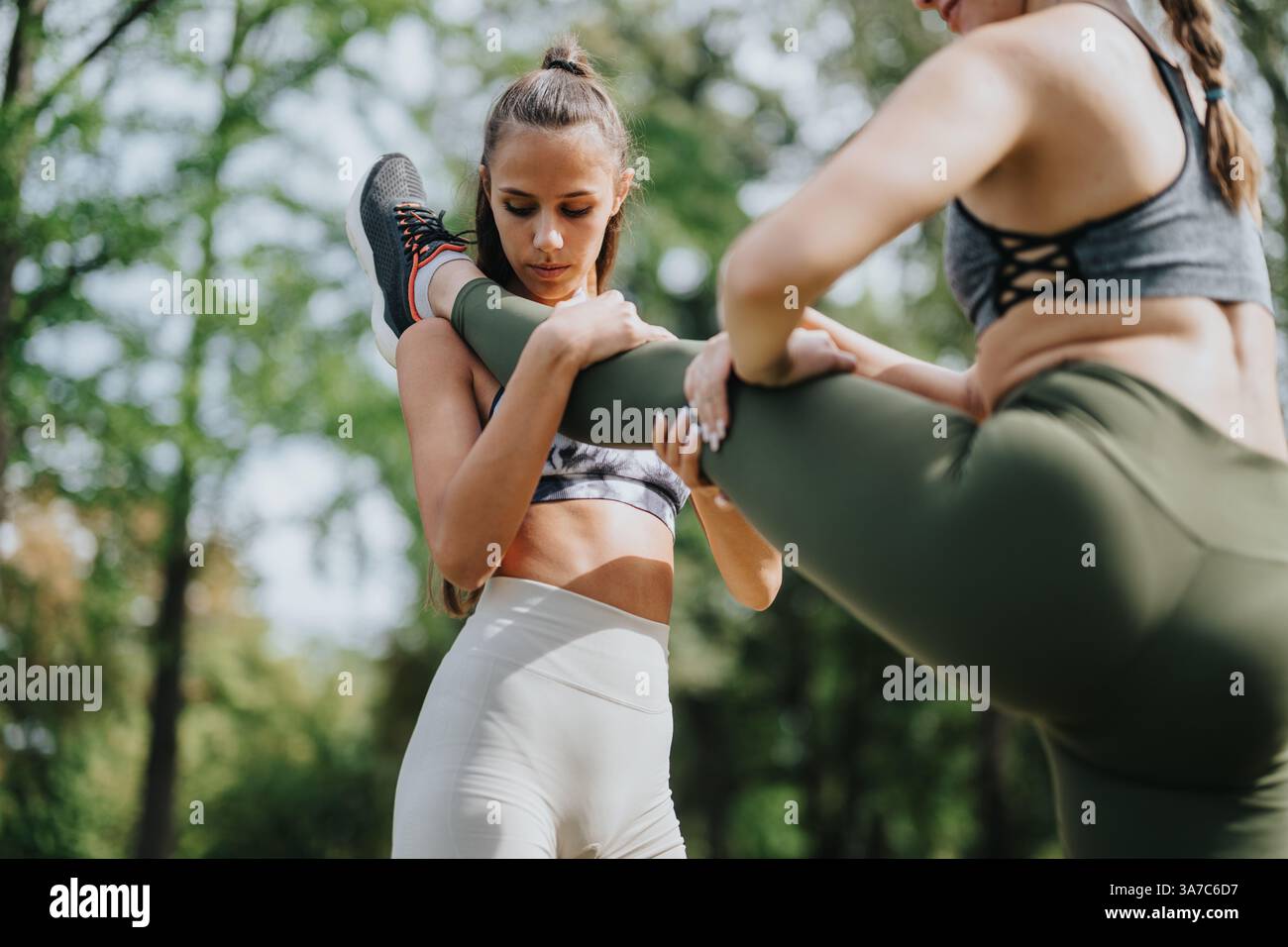 Two women stretching together in a park while practicing outdoor ...