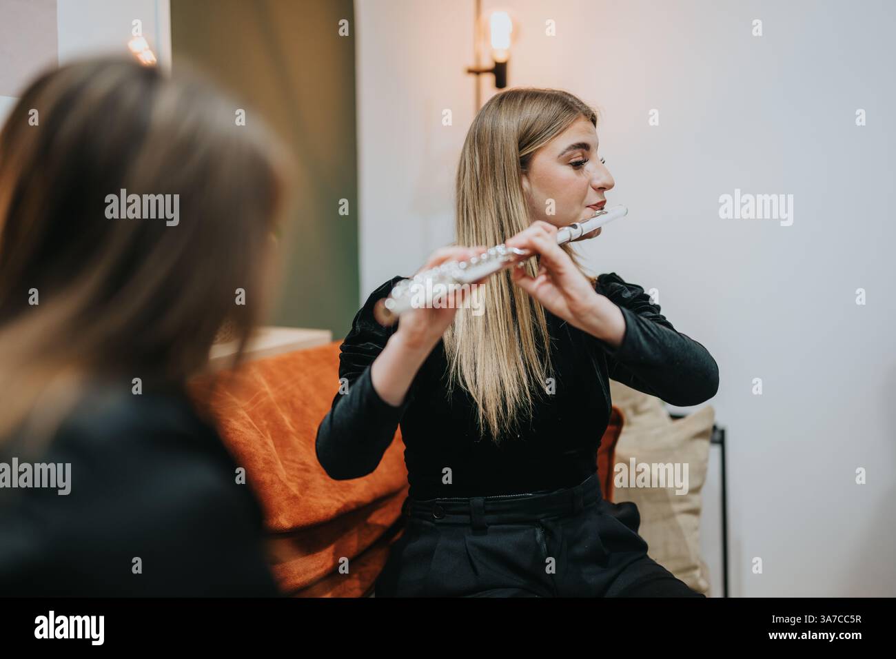 A woman seated inside playing a flute, immersed in a melodic ...