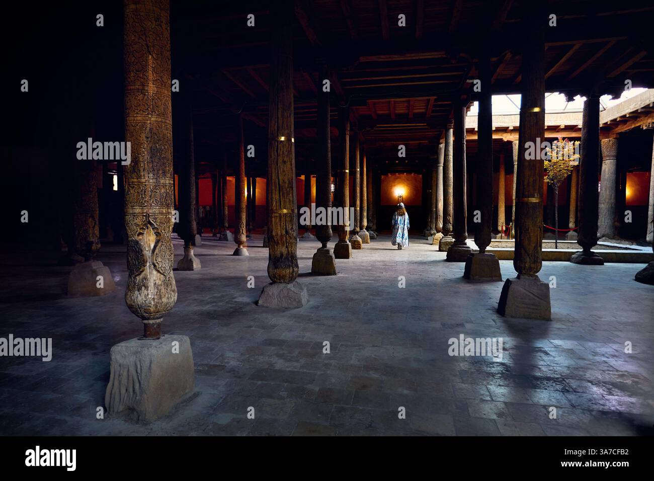 Woman tourist in ethnic dress at old hall with wooden column of Juma ...