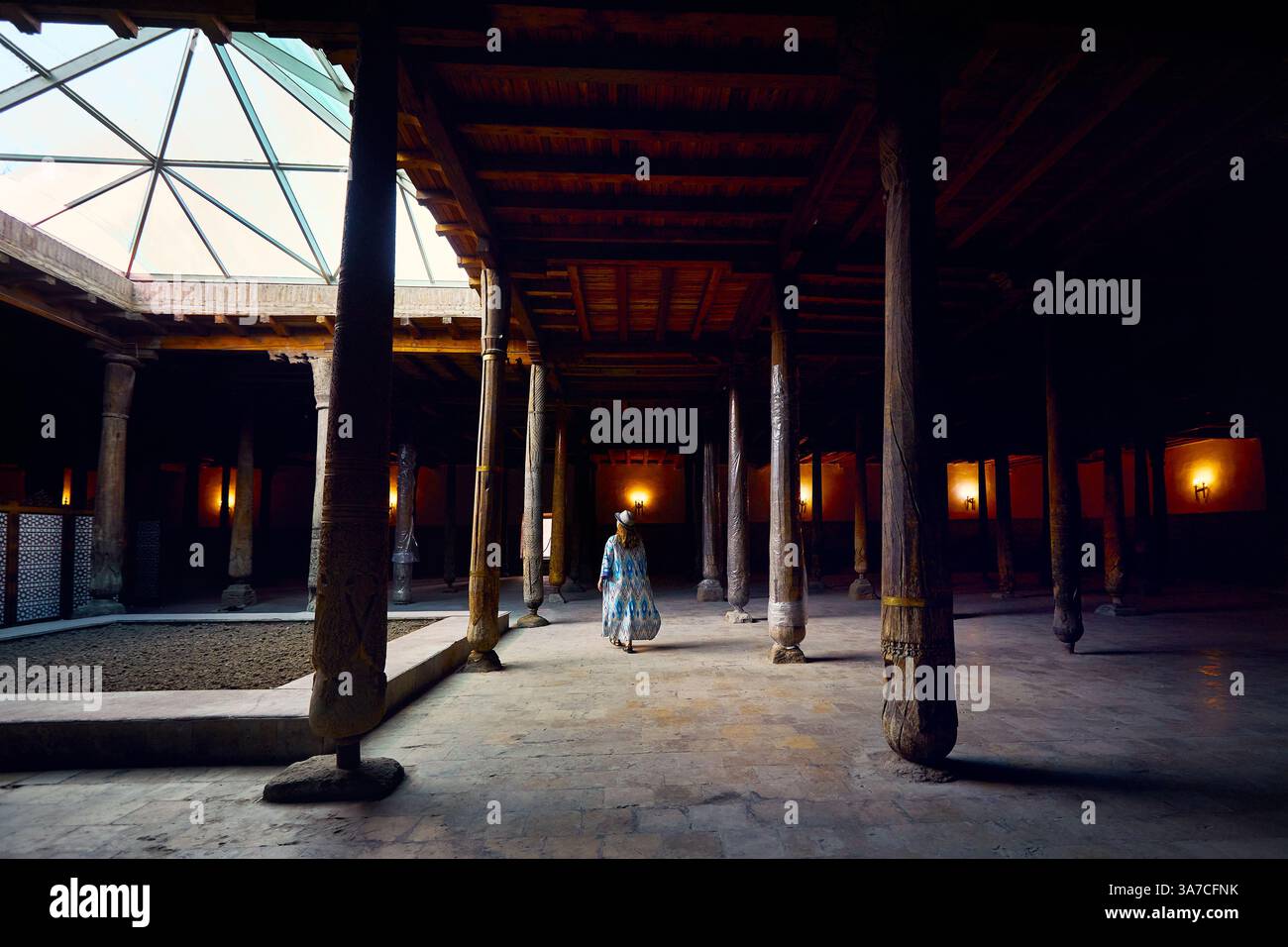 Woman tourist in ethnic dress at old hall with wooden column of Juma ...