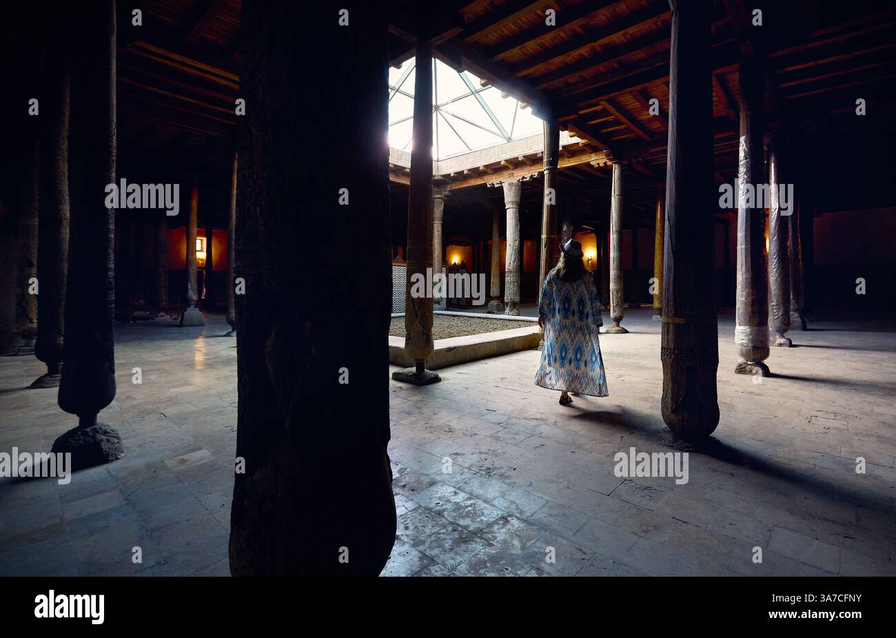 Woman tourist in ethnic dress at old hall with wooden column of Juma ...