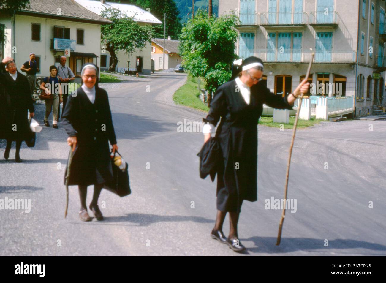 A group of nuns and fellow walkers make their way along a quiet road in ...