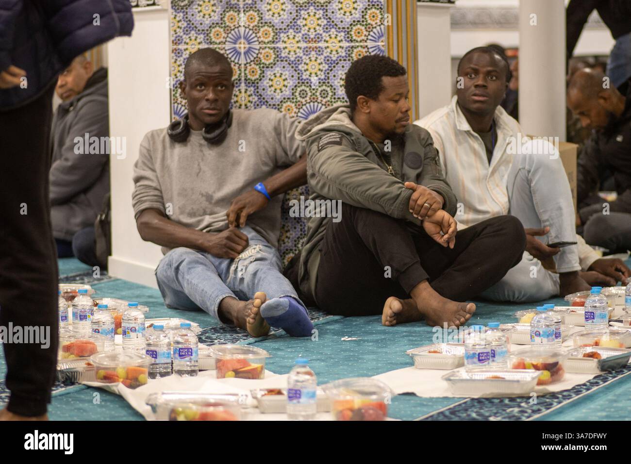 Madrid, Spain. 26th Mar, 2025. A group of men share Iftar, the meal ...