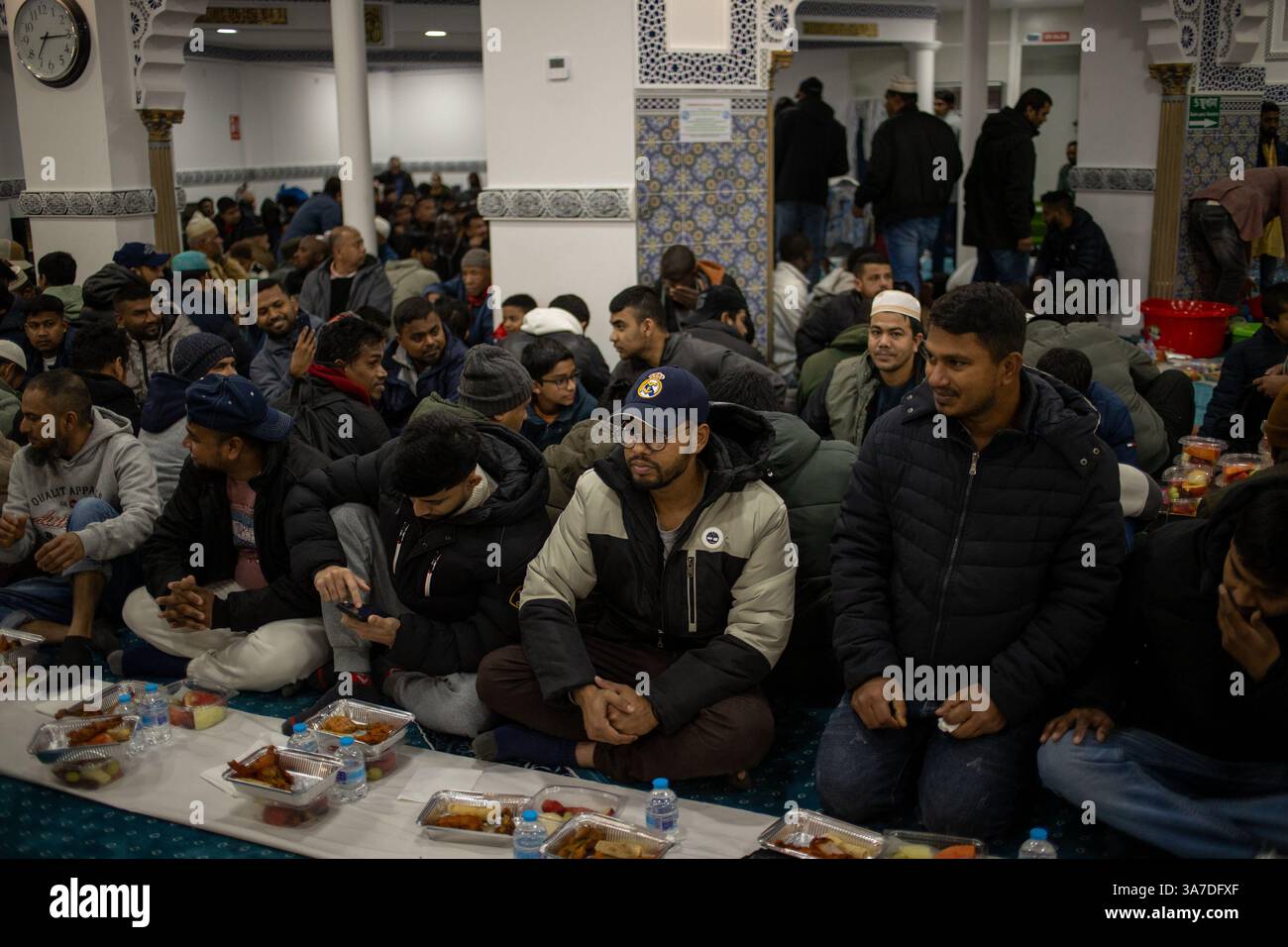 Madrid, Spain. 26th Mar, 2025. A group of men share Iftar, the meal ...