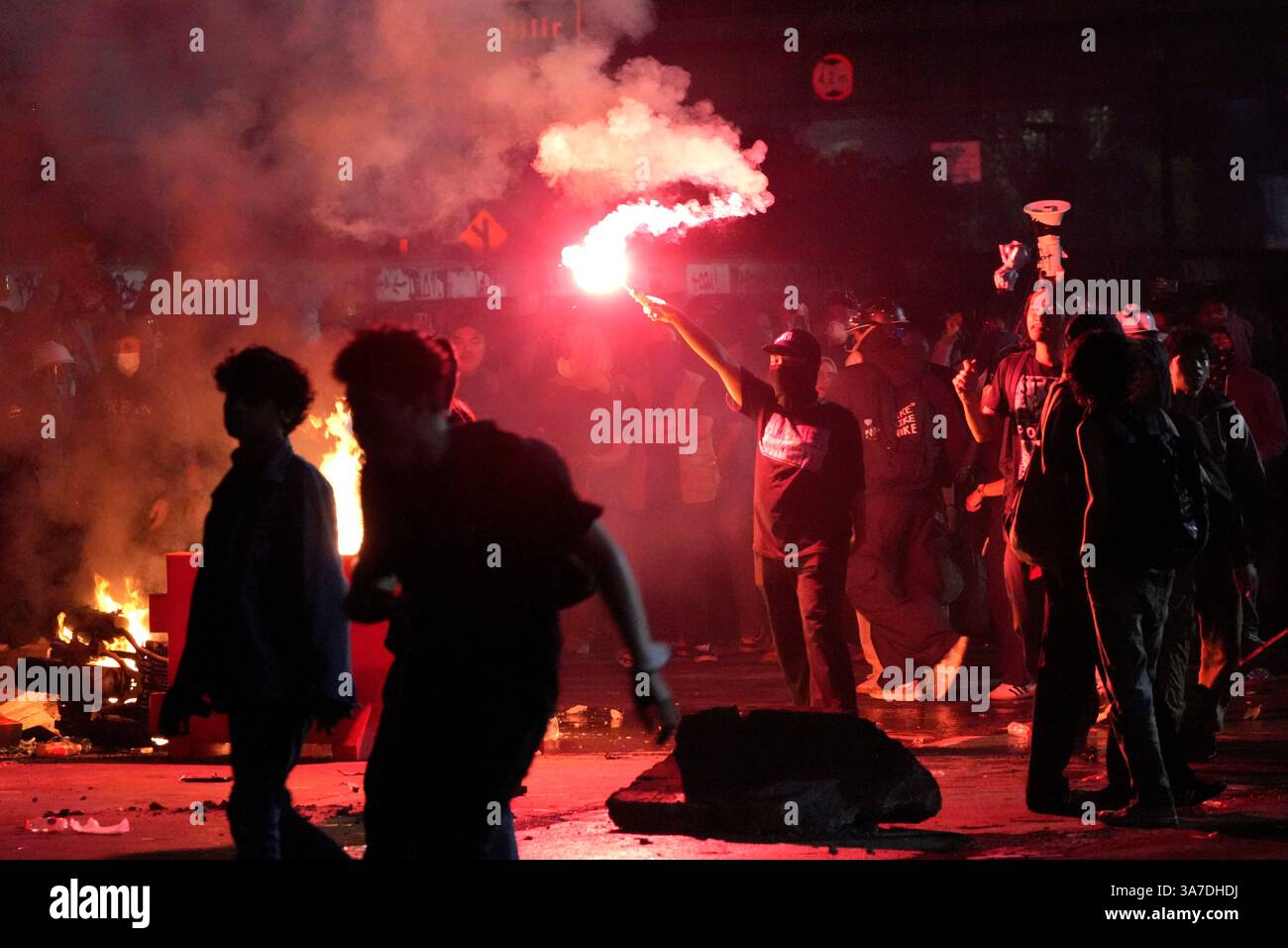A protester lights a flare during a rally against the passing of a ...