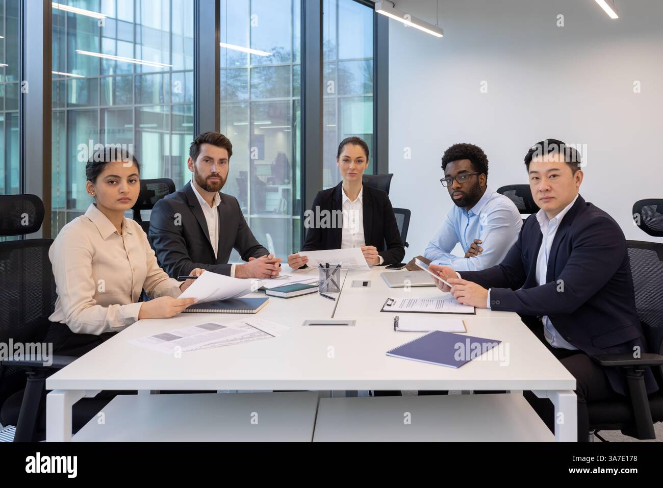 A diverse team of professionals gathers around a modern conference ...