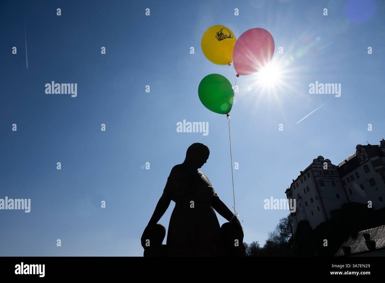 27 March 2025, Hesse, Weilburg: Colorful balloons hang on a bridge over ...