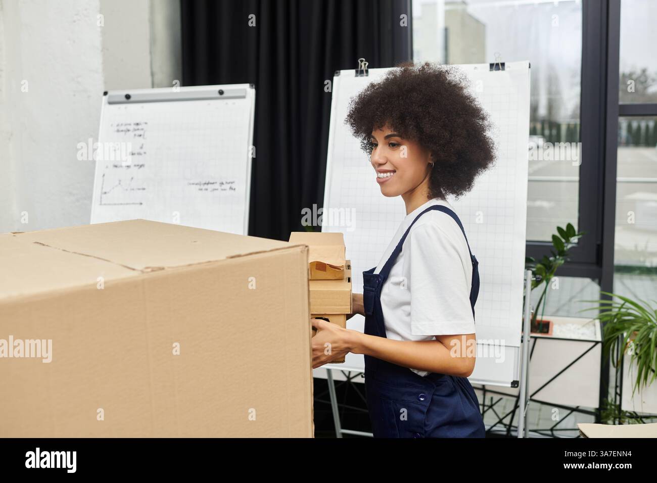 A woman is packing items into boxes in a contemporary office setting ...