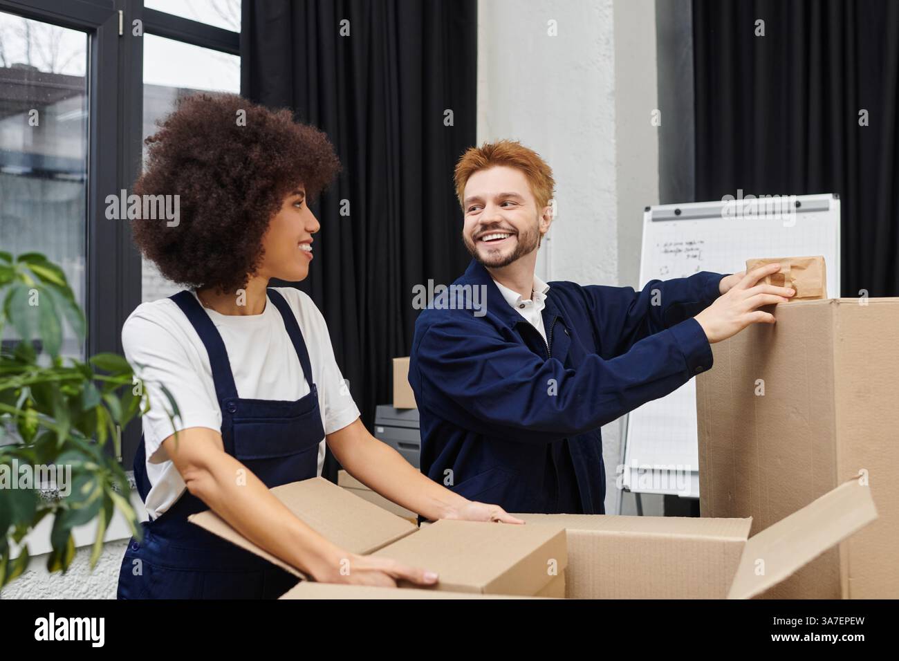 Two people happily pack and unpack boxes with their belongings in a ...