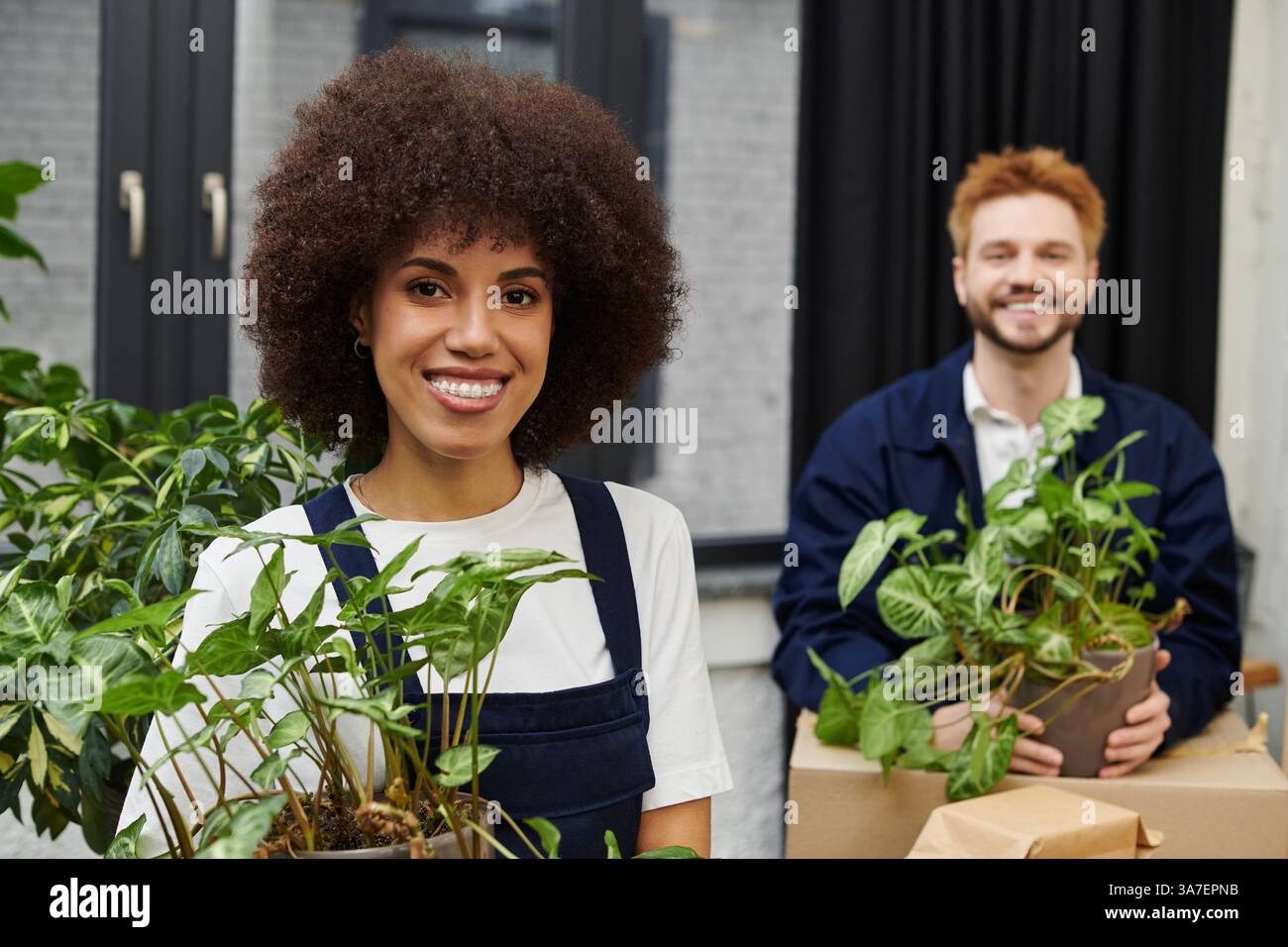 Two friends joyfully unpack indoor plants together in a contemporary ...