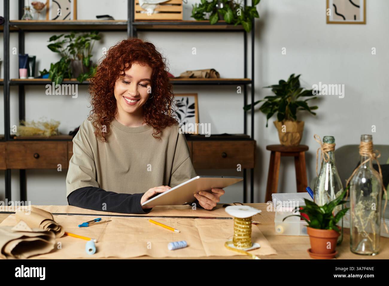 A young woman smiles as she designs a DIY project in her plant filled ...