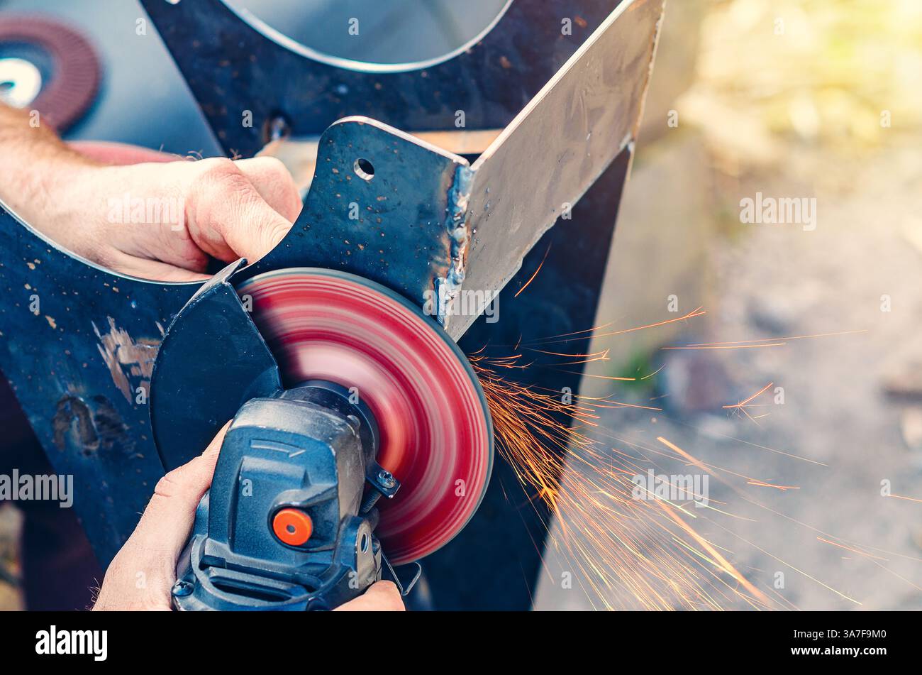 Hand using angle grinder to cut metal with sparks in outdoor ...