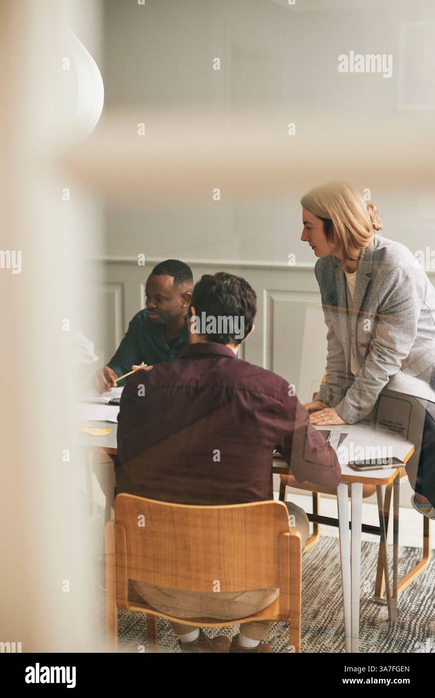 Rear view of businessman sitting at conference table during meeting ...