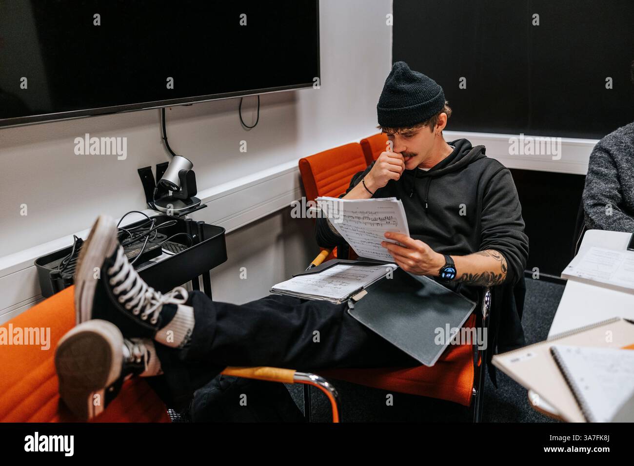 Focused young male student reading book while sitting with legs crossed ...