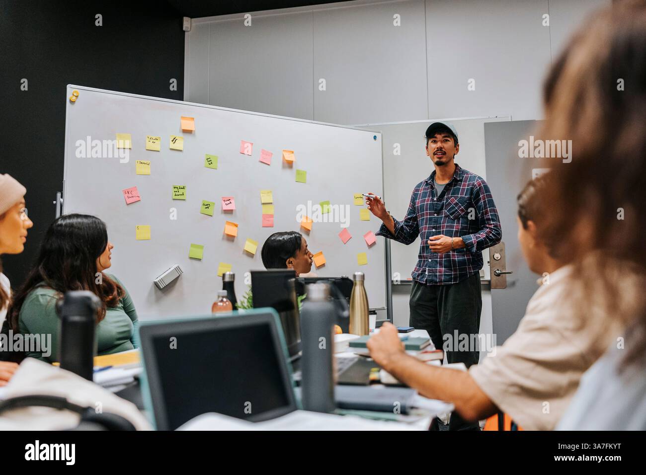 Male student doing project planning with classmates in classroom at ...