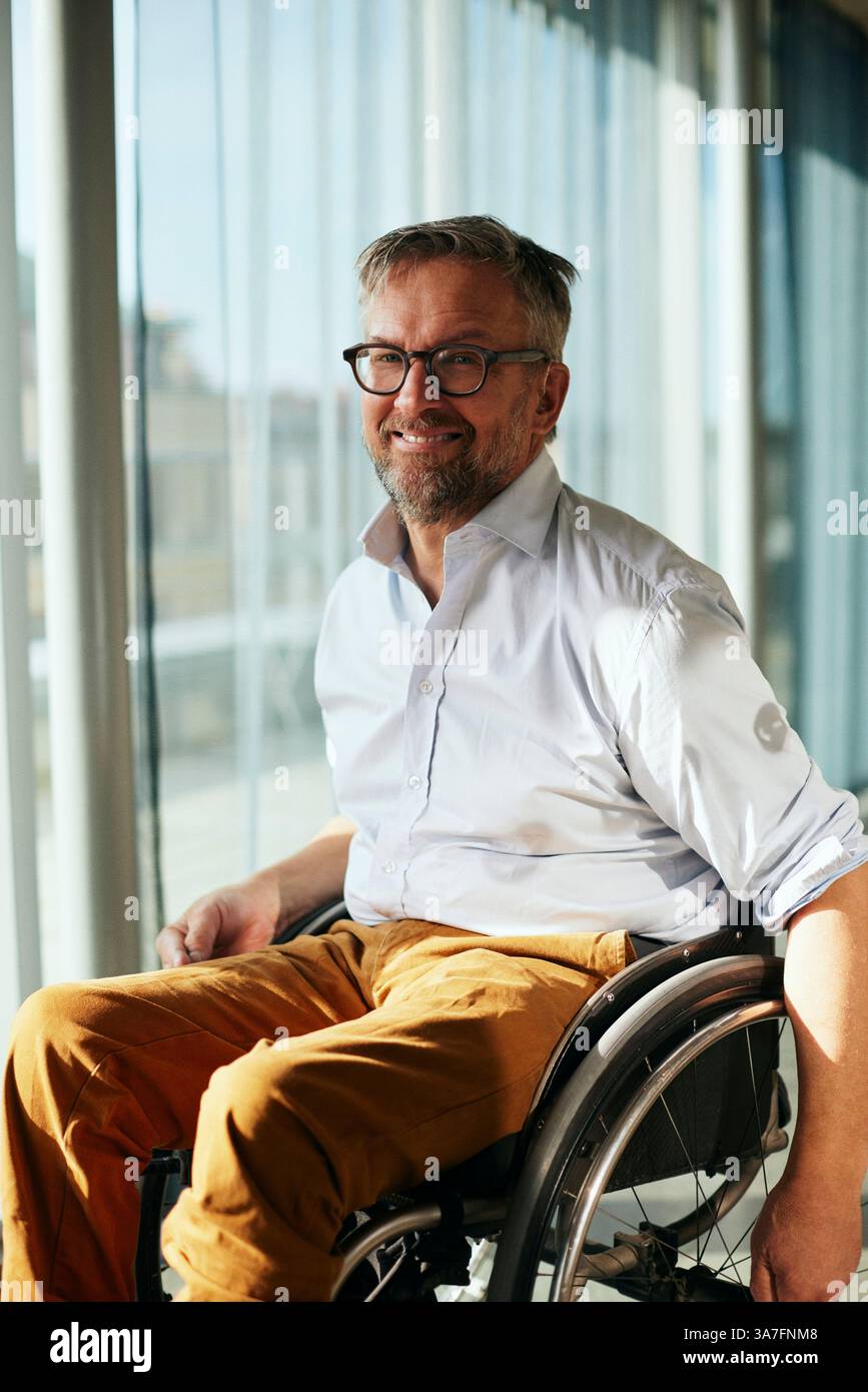 Portrait of happy male business professional with disability sitting on ...