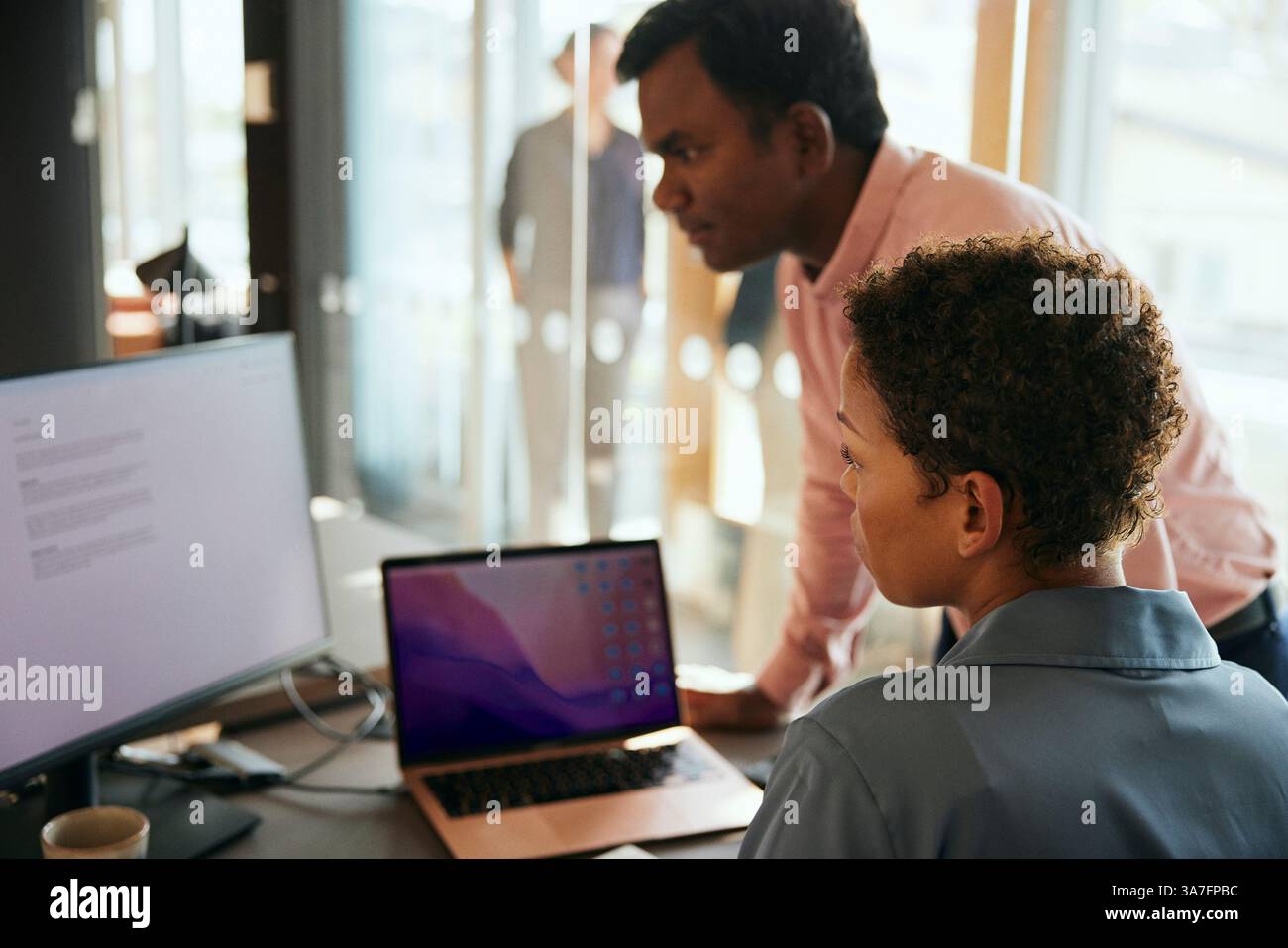 Female and male business professionals working on desktop PC in office ...