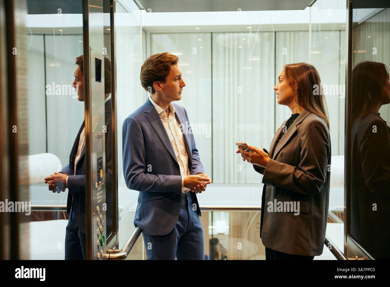 Male and female business professionals talking with each other while ...