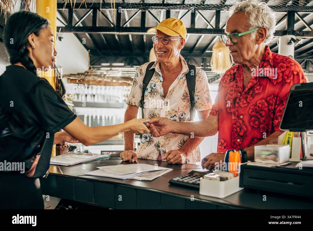 Senior gay couple talking with receptionist while checking in at ...
