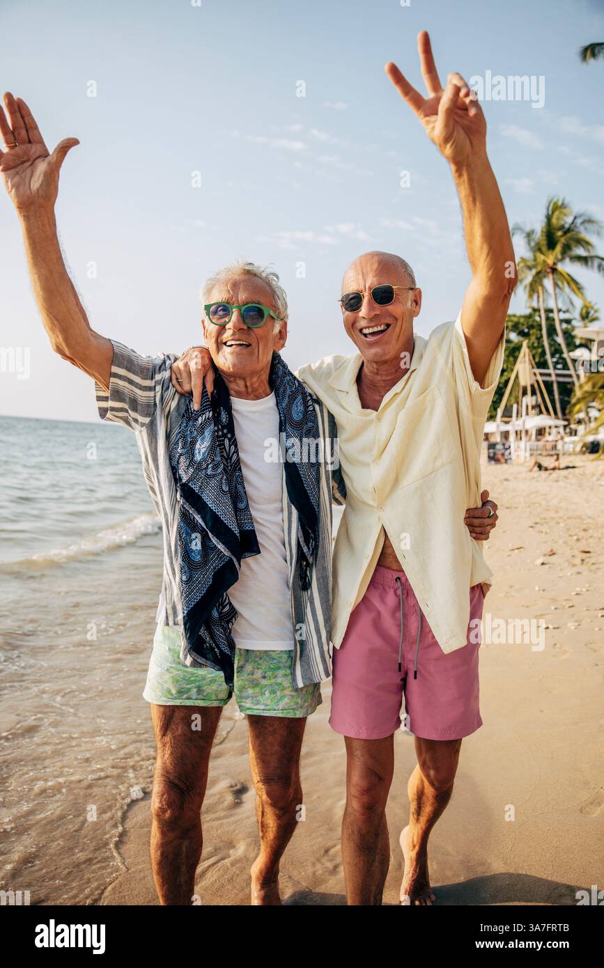 Happy senior man gesturing peace sign while walking with boyfriend on ...