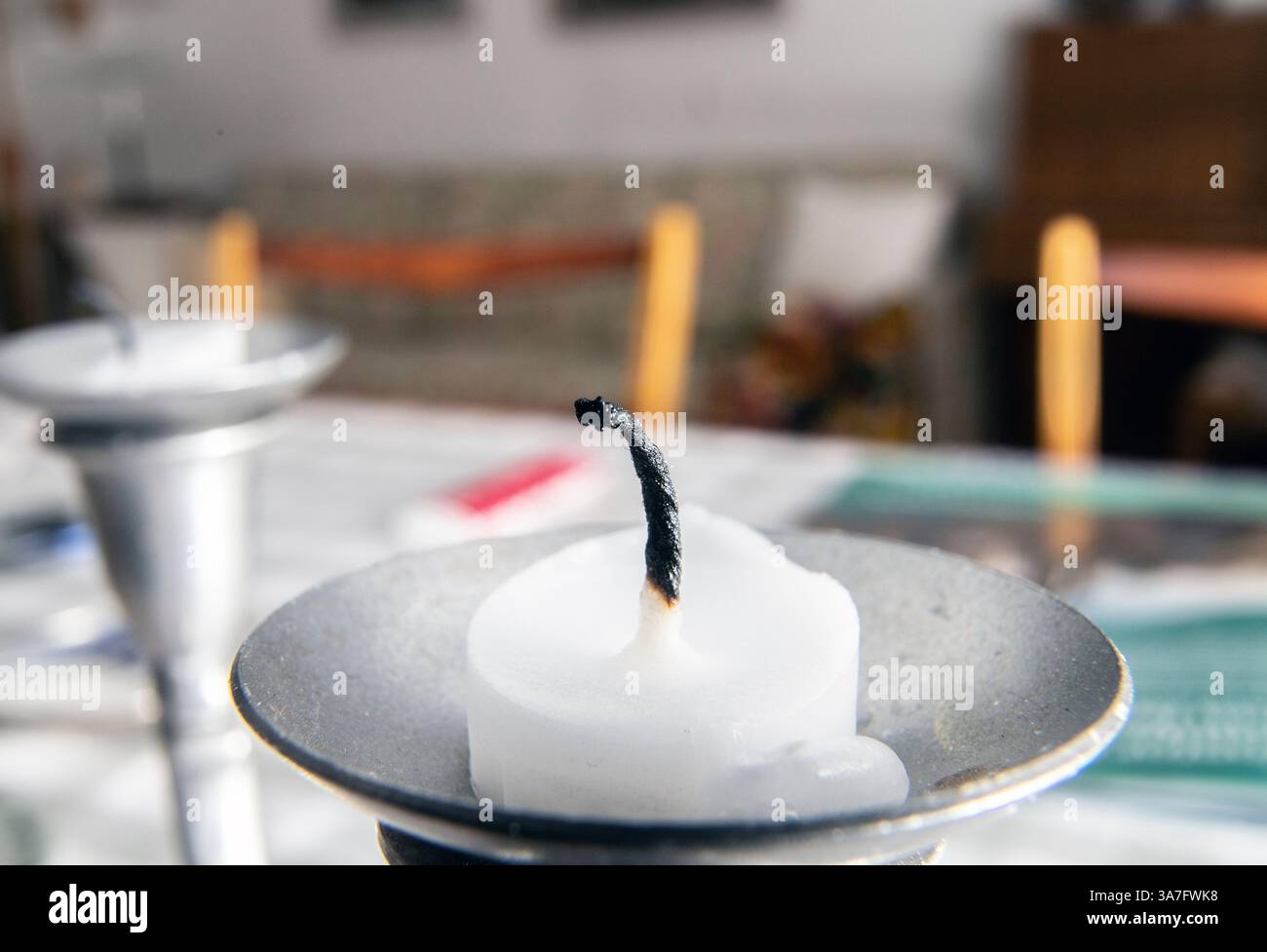 Stump of stearin candle with black-fired wick in metal candlestick ...