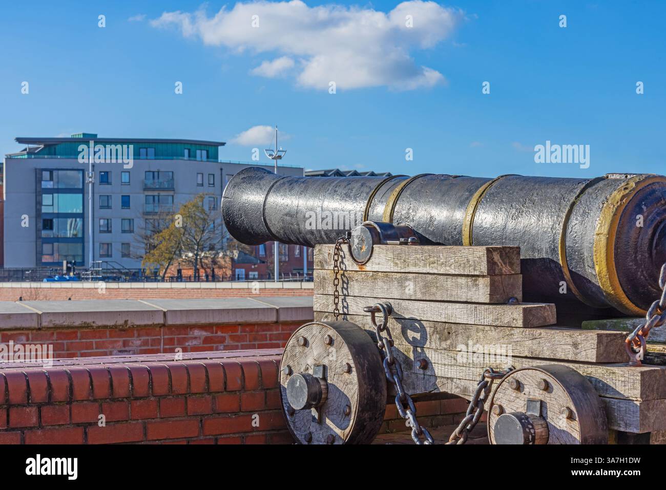An old cannon displayed on a raised brick mounting in a marina. There ...