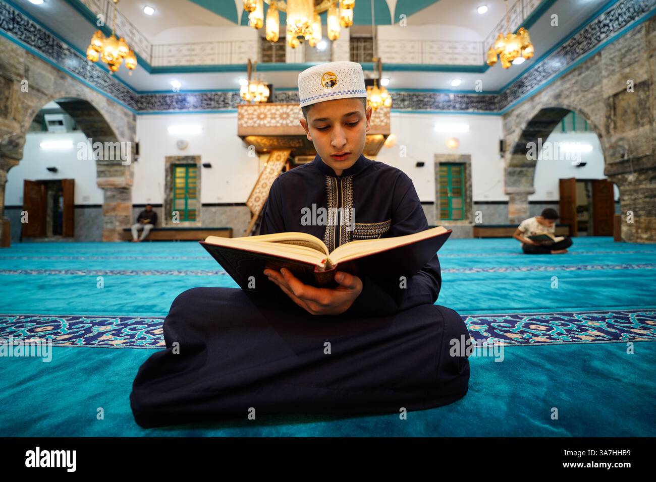 March 26, 2025, Mosul, Nineveh, Iraq: A young Sunni Muslim boy reads ...