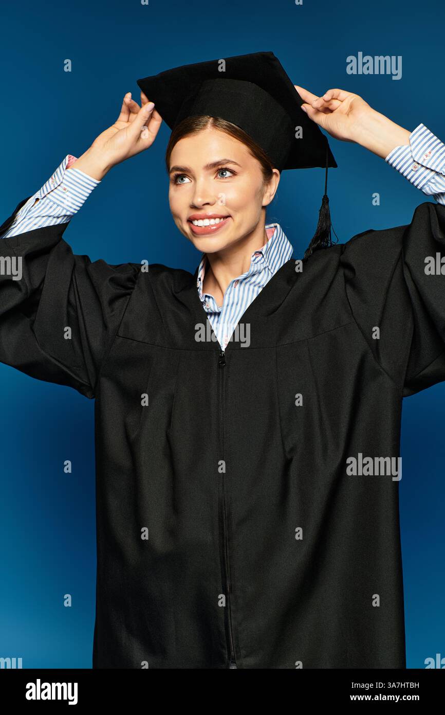 A young woman smiles as she adjusts her graduation cap, radiating ...