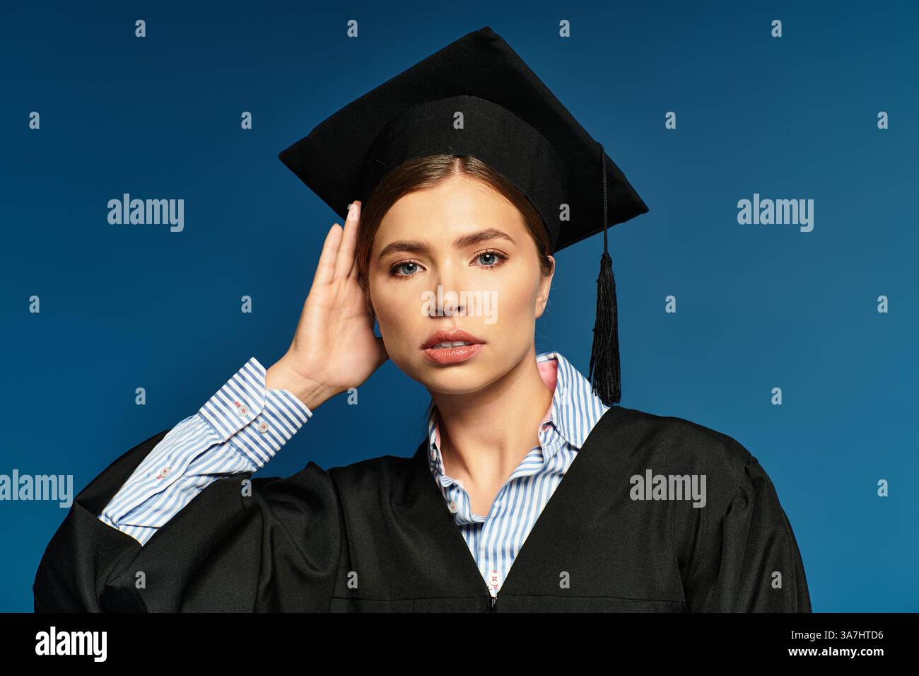 A proud young woman in a graduation cap and gown celebrates her ...