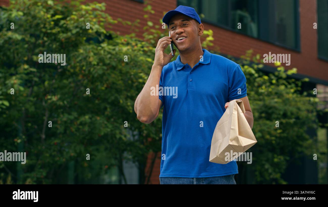 African American courier man talking call client mobile phone holding ...