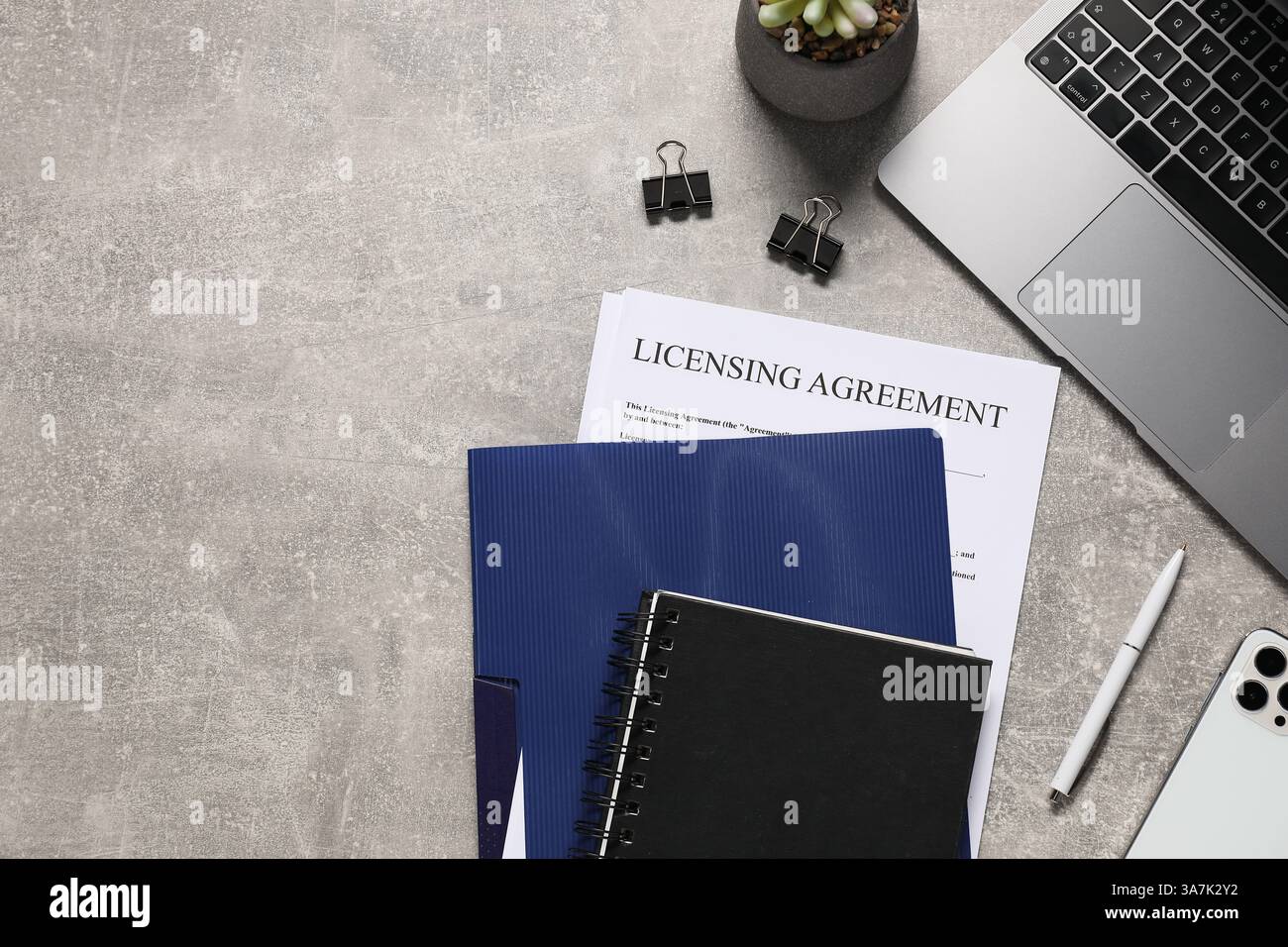 Licensing agreement document, stationery, laptop and smartphone on gray ...