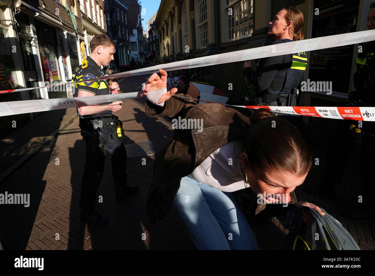 A person walks past police officers and under police tape of a cordoned ...