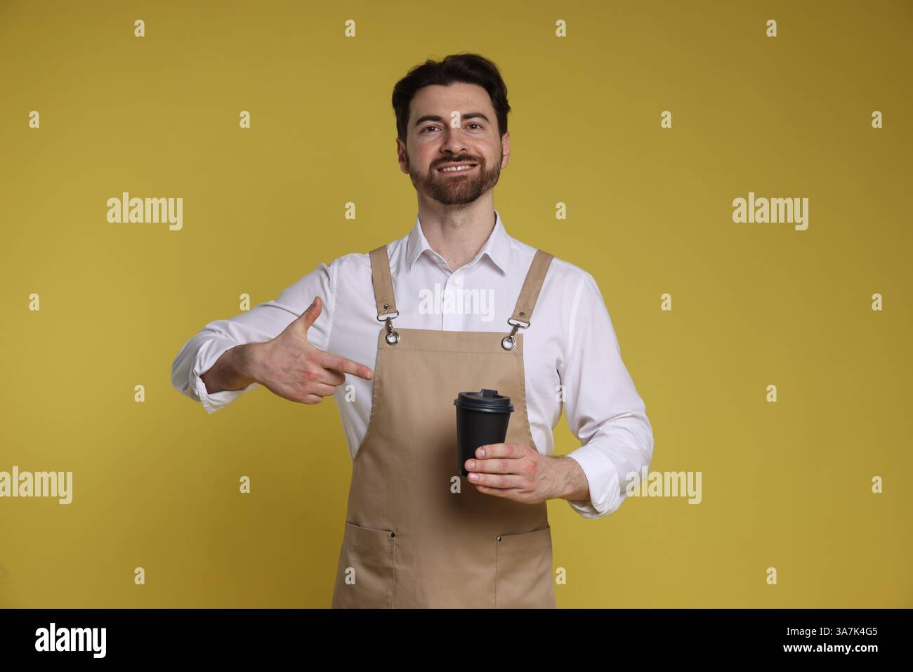 Portrait of smiling barista pointing at paper takeaway cup of hot drink ...