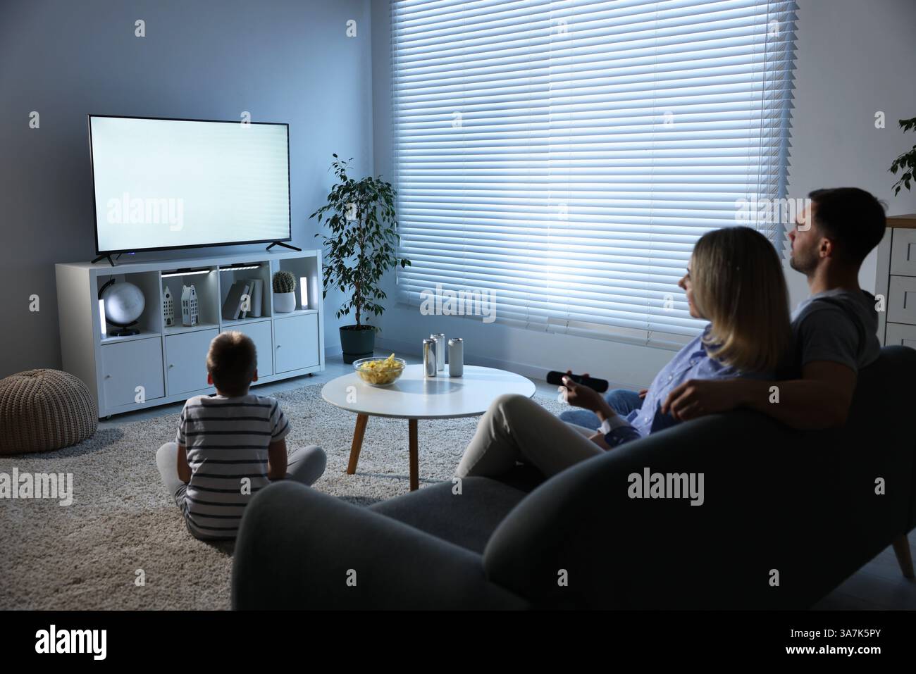 Happy family with snacks and drinks watching tv together at home Stock ...