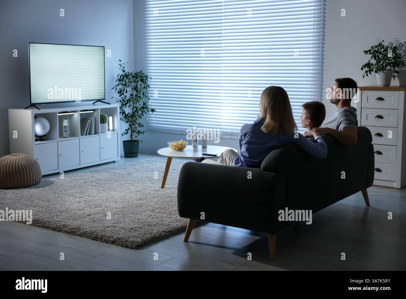 Happy family with snacks and drinks watching tv together at home Stock ...