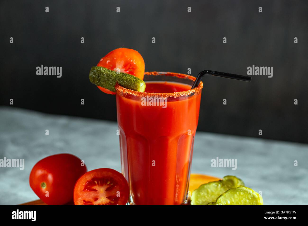 Bloody Mary cocktail in glass served with tomatoes and pickles on grey ...