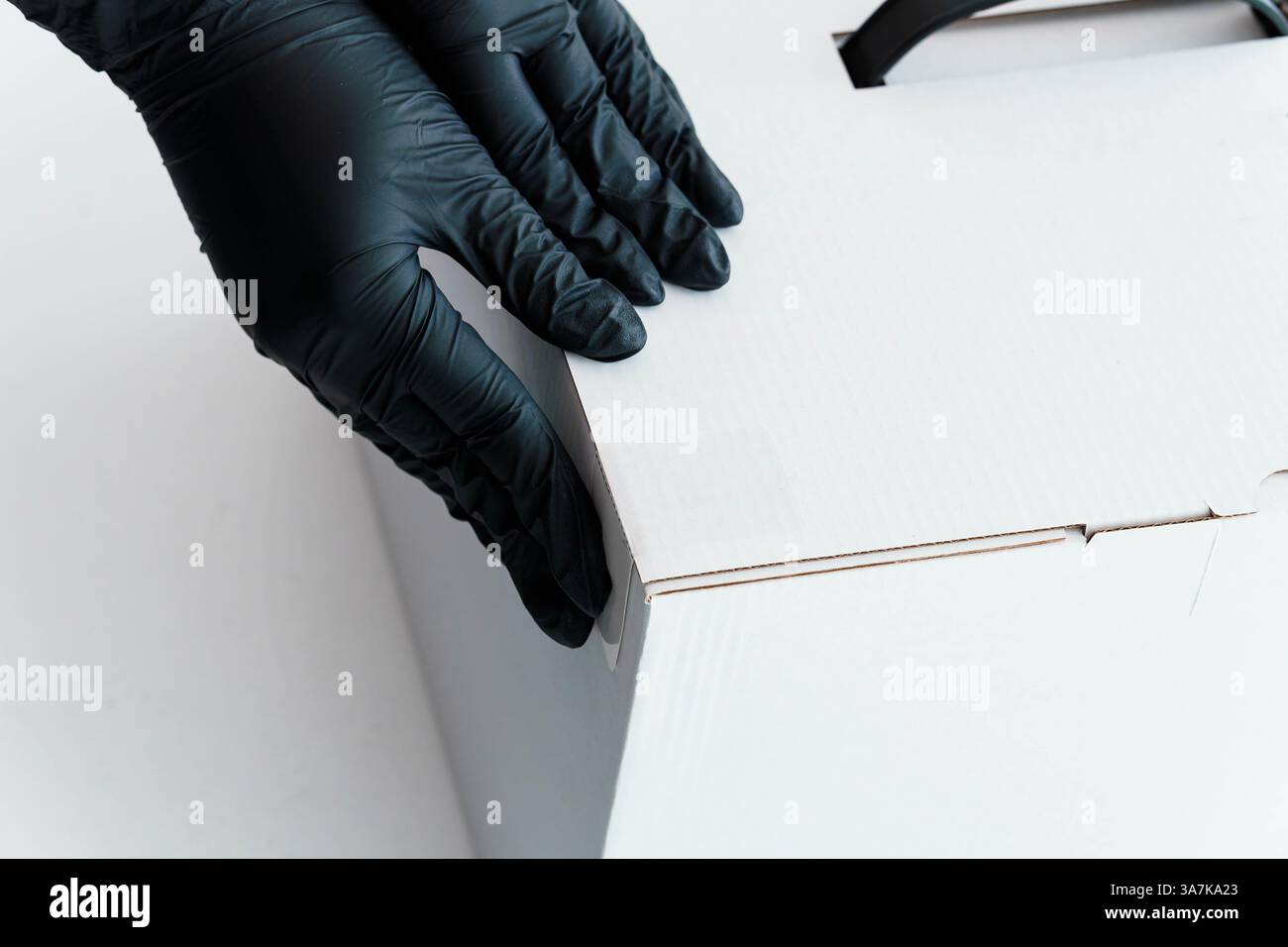 Close-up View of Hand Wearing Black Gloves Handling White Cardboard Box ...