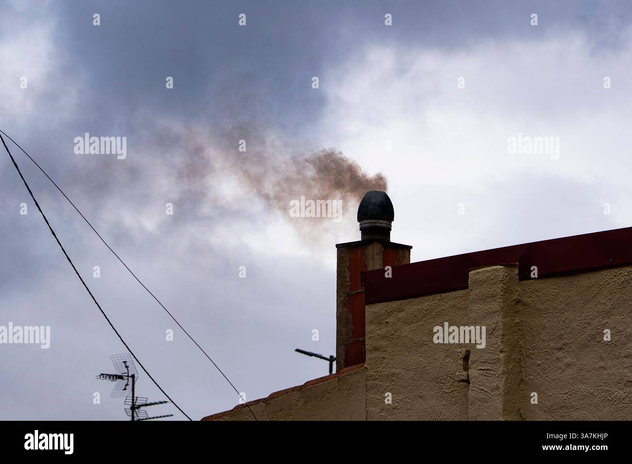 Smoke from a wood fire exiting a chimney stack in a town in Catalonia ...