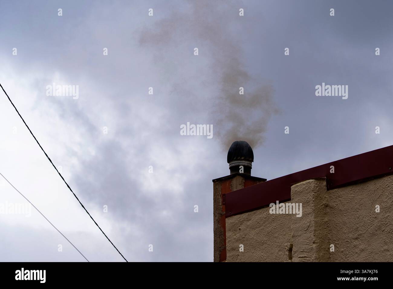 Smoke from a wood fire exiting a chimney stack in a town in Catalonia ...