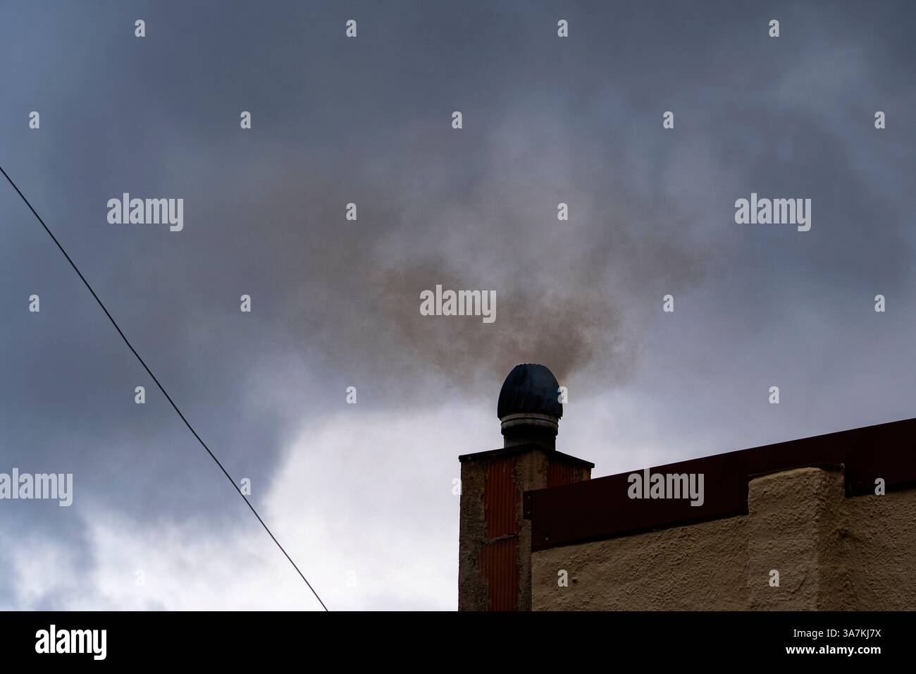 Smoke from a wood fire exiting a chimney stack in a town in Catalonia ...