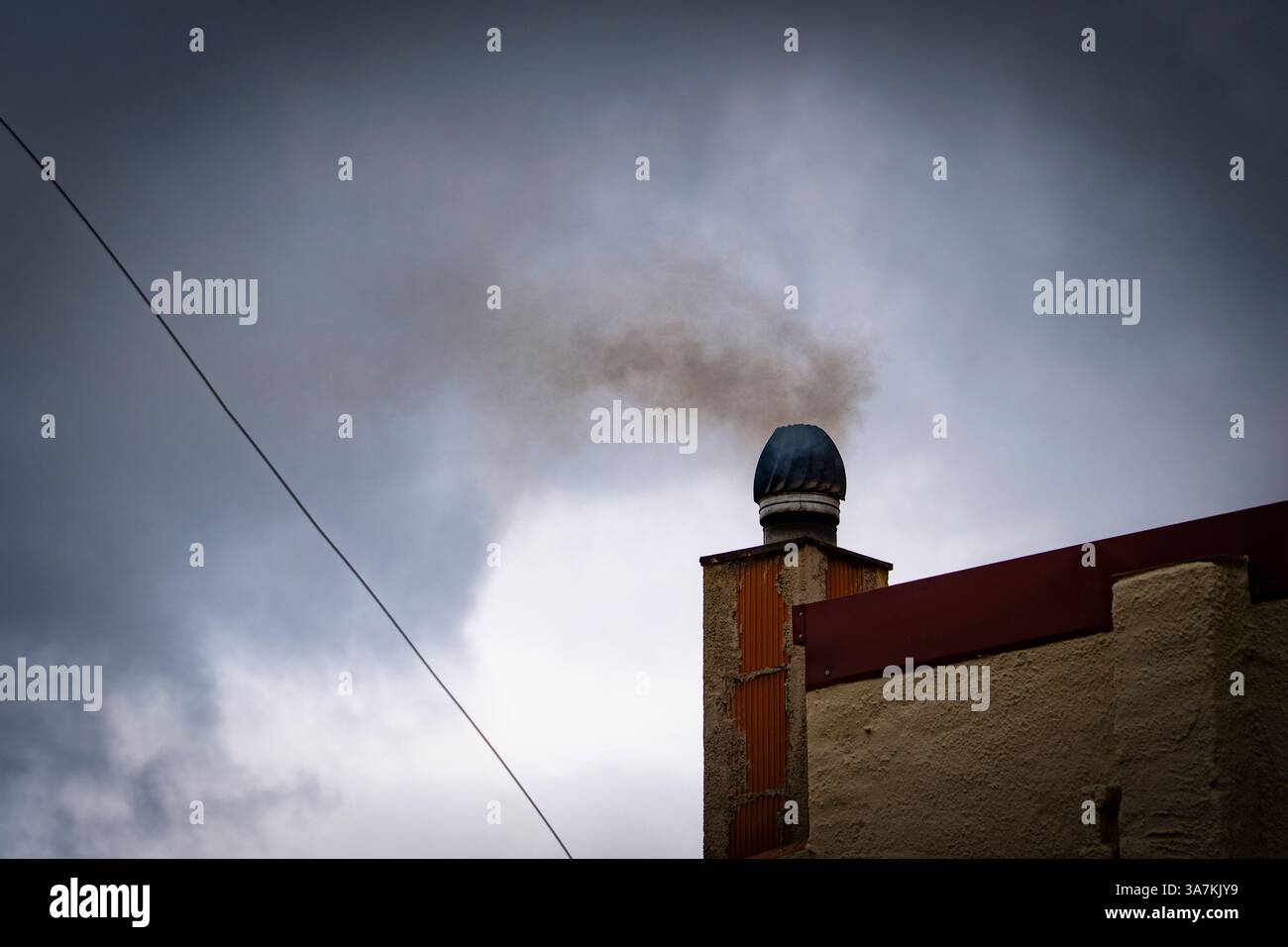 Smoke from a wood fire exiting a chimney stack in a town in Catalonia ...