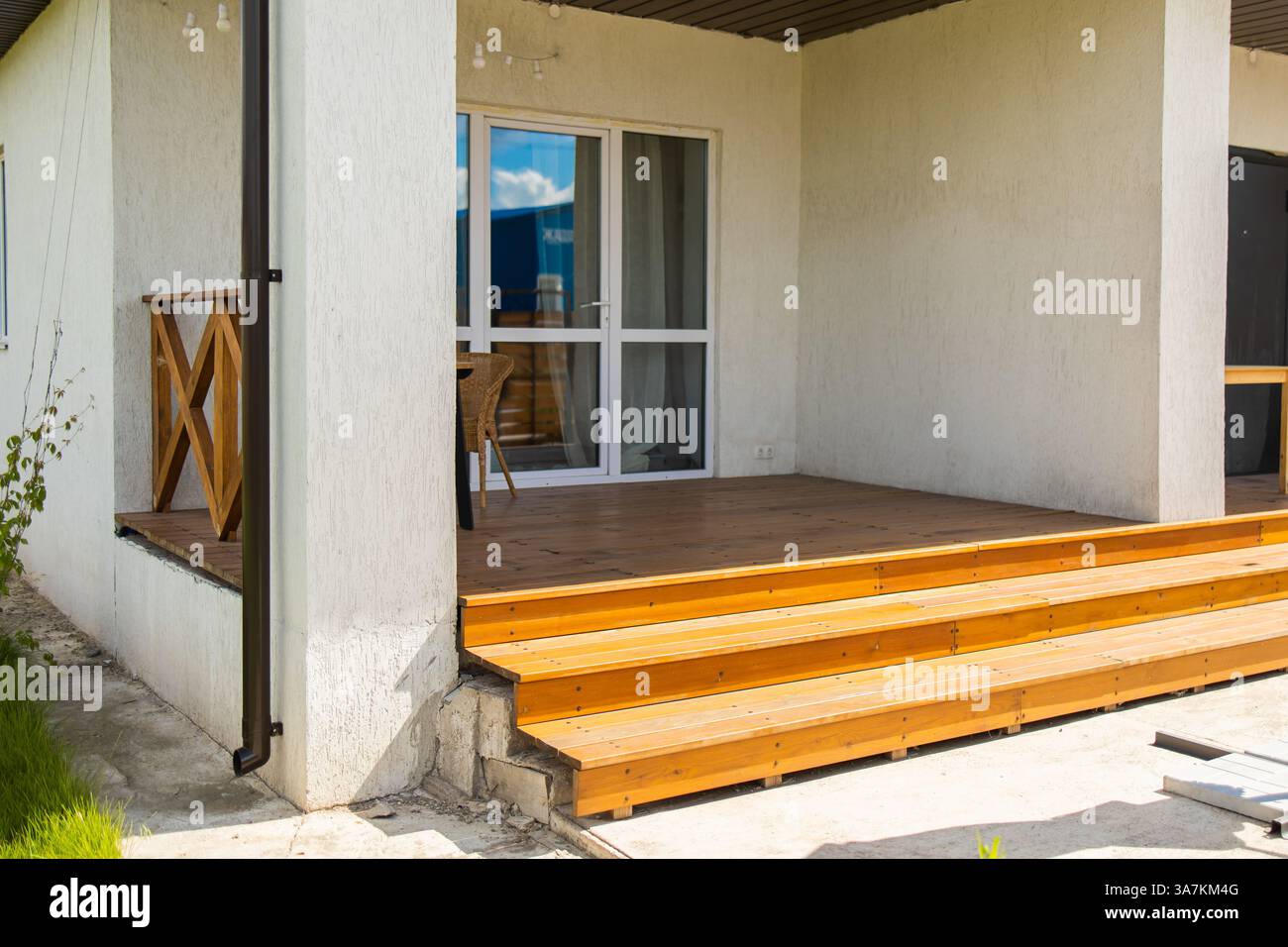 Wooden terrace with glass door and wicker chair. Functional residential ...