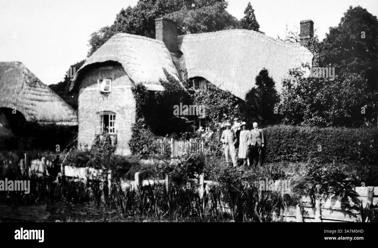 A group of people standing near a thatched cottage in Hunton, a village ...