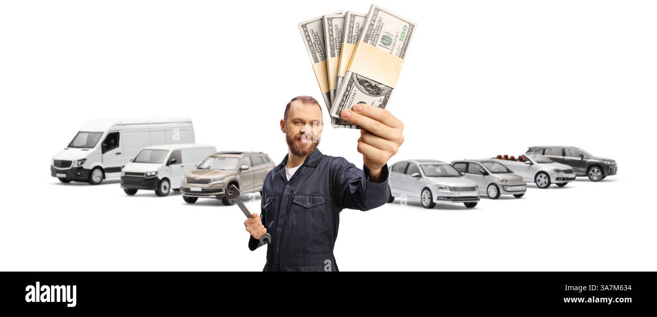 Car mechanic in a uniform holding a wrench and money at a car park ...